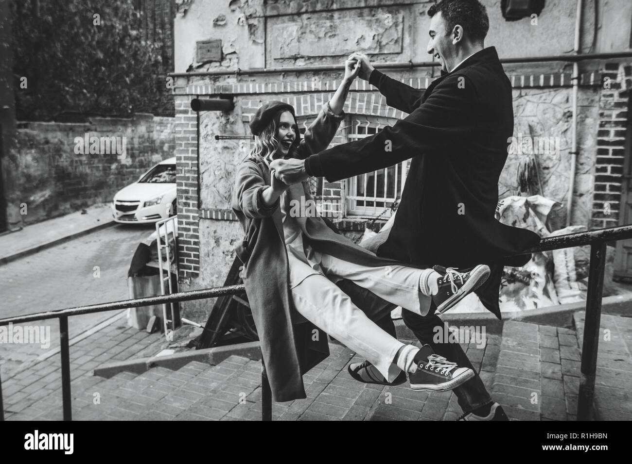 Woman funny slides down the stair railing. Young couple having fun ...