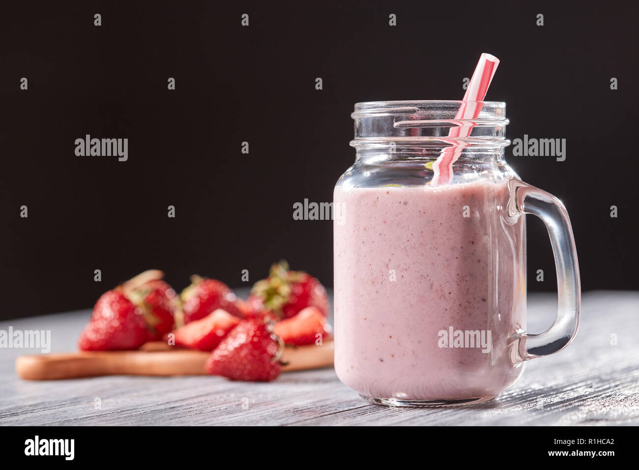 Homemade strawberry milk shake in a jar with a straw on a wooden table ...