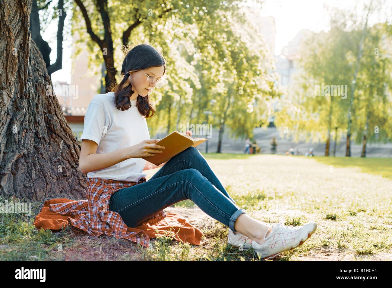 Girl Reading A Book Under A Tree
