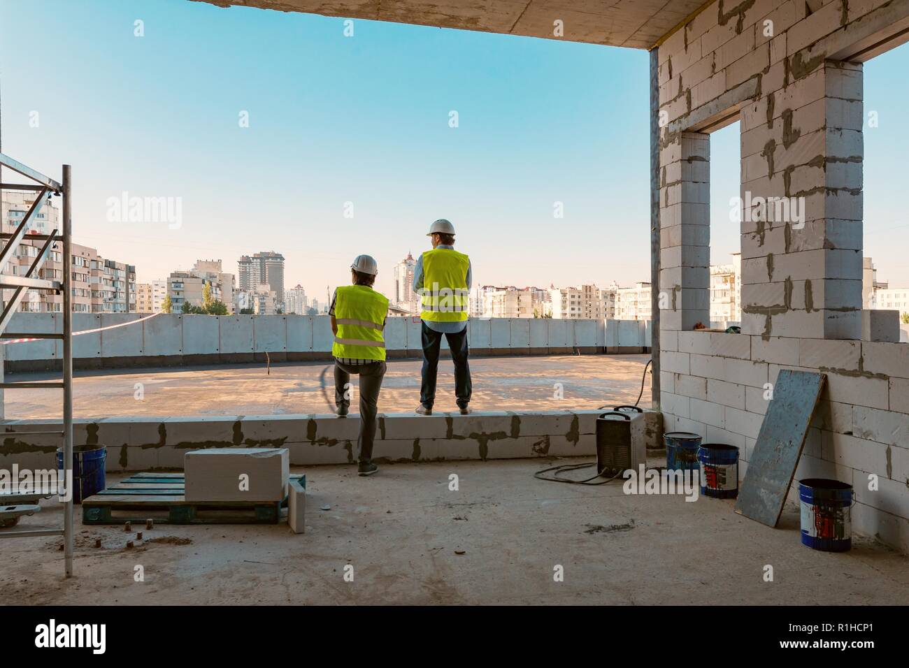 Two male builders at a construction site. Men looking into the distance ...