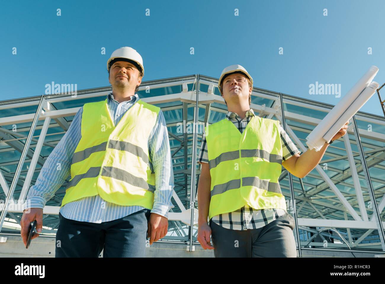 Male construction worker and engineer at the construction site ...