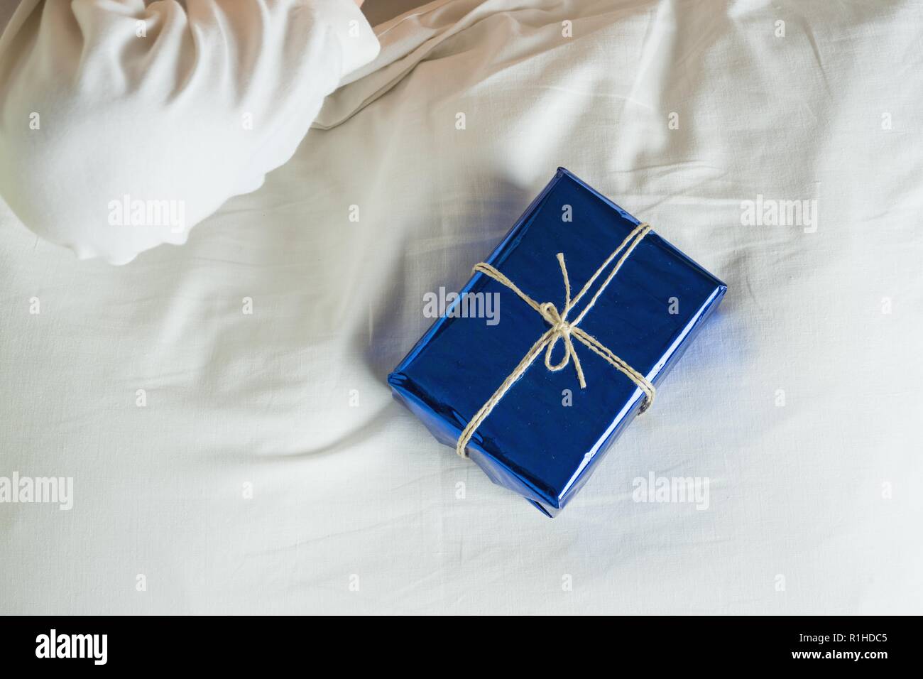 Gift surprise in bed, blue packed box on white bed Stock Photo - Alamy