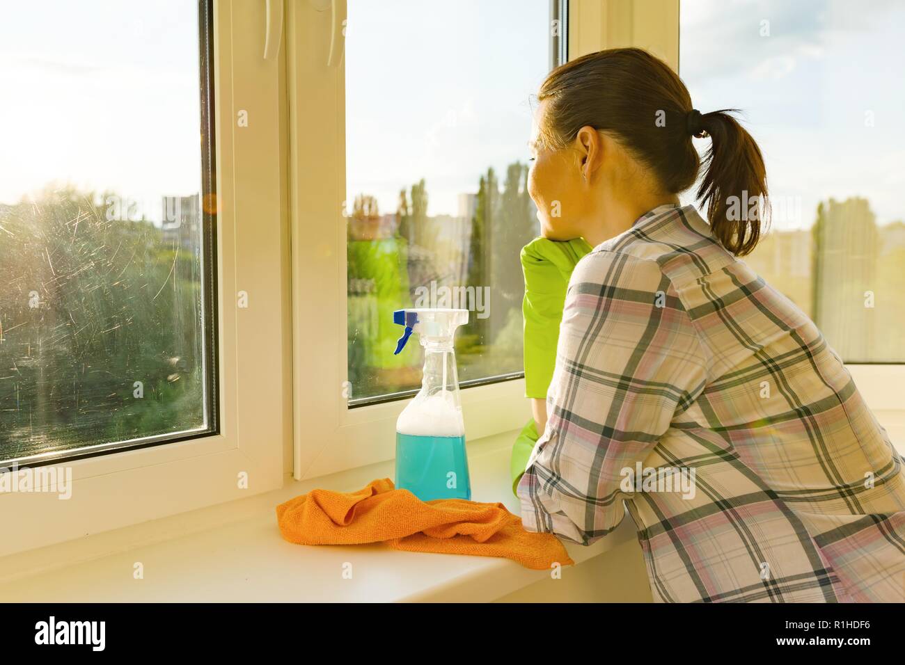 Adult woman washes windows, cleaning the house, female looks into a ...