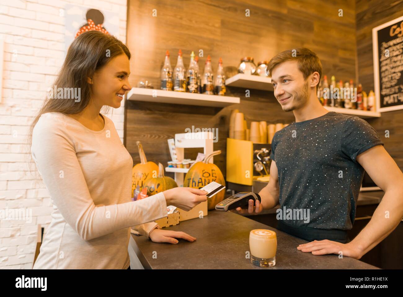 Girl coffee shop client pays coffee by credit card, barista holding a ...