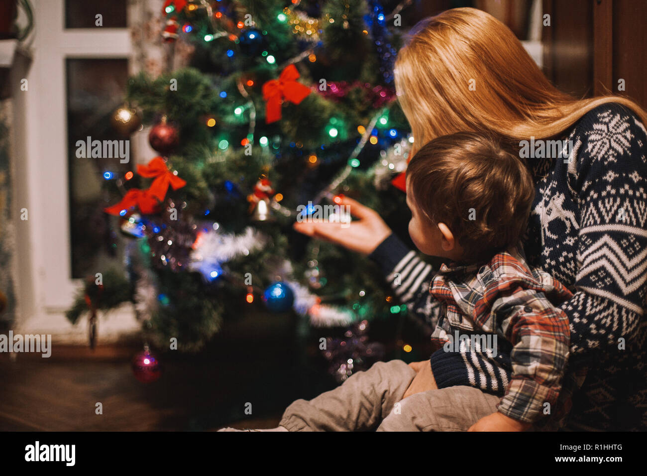 Mother showing Christmas bell to baby boy while sitting beside ...