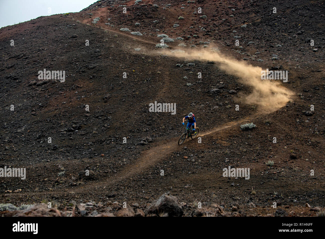 A man rides a mountain bike on volcanic terrain near la Piton de la ...