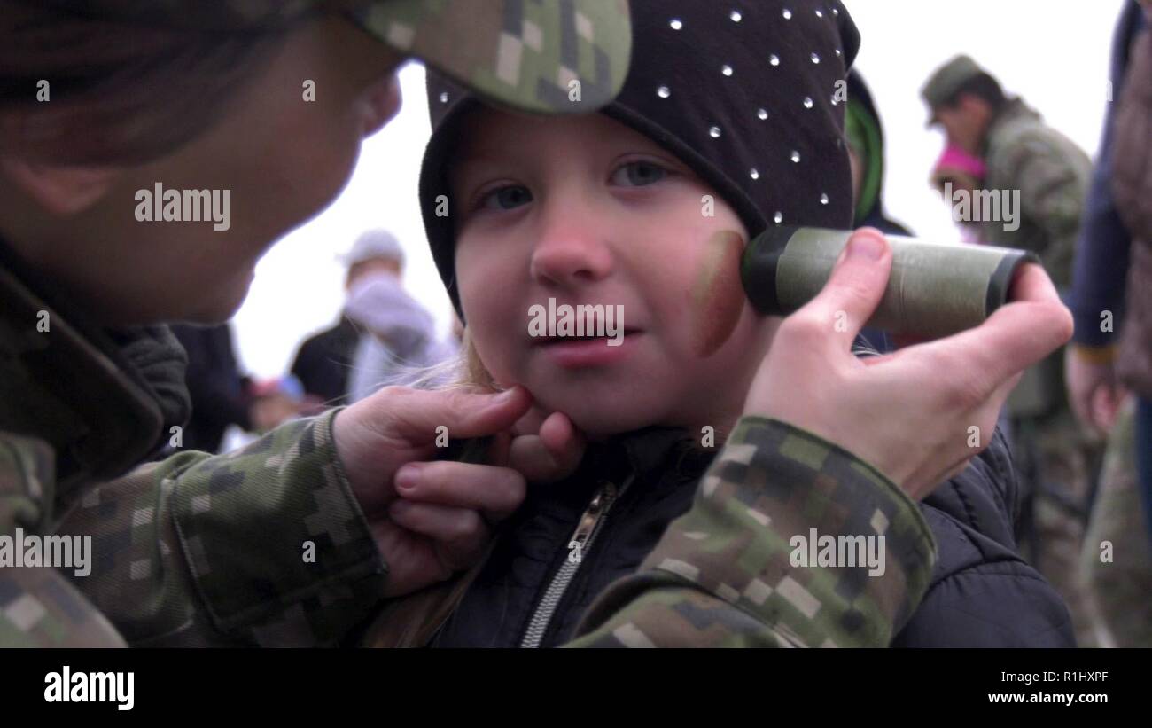A Slovakian Army Soldier puts face paint on a young girl during Armed ...
