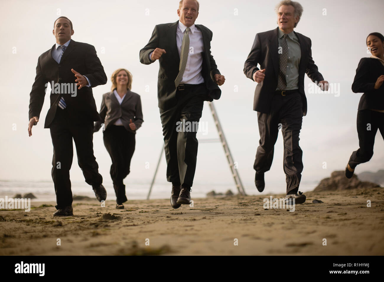 Colleagues running on beach Stock Photo - Alamy