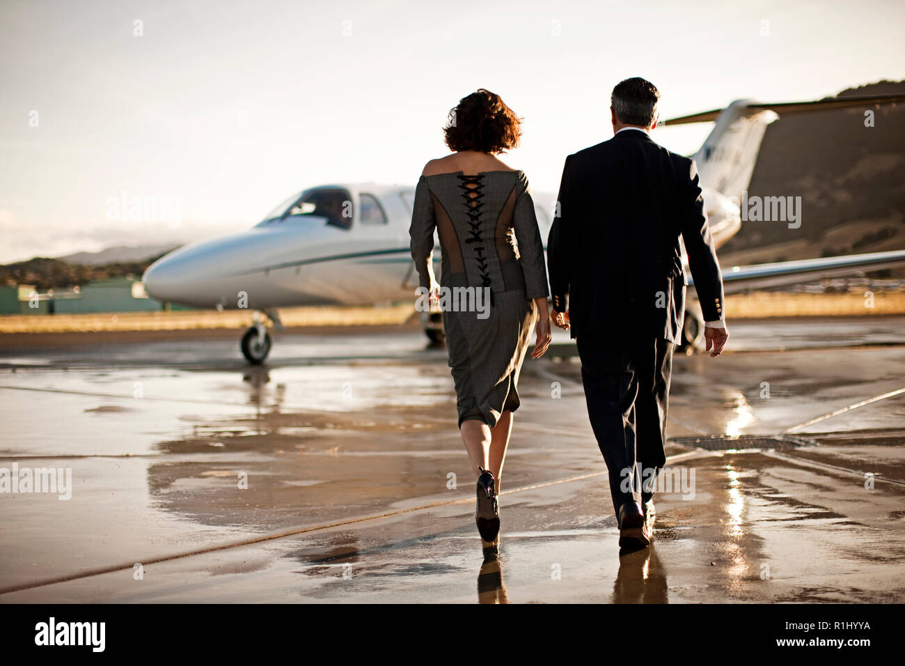 Well-dressed couple walking towards a private jet Stock Photo - Alamy
