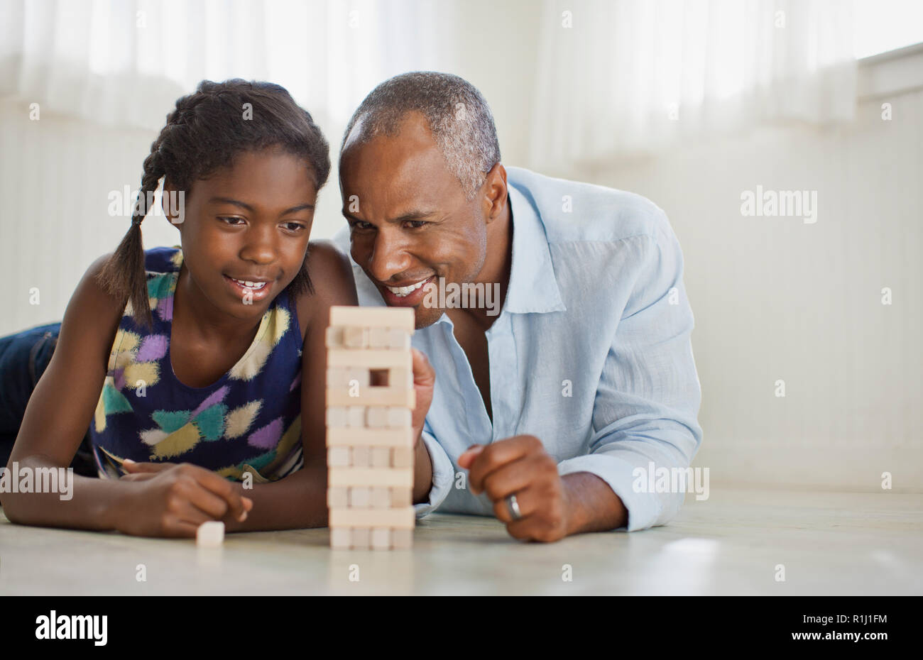 Smiling father and daughter playing with a block removal game Stock ...