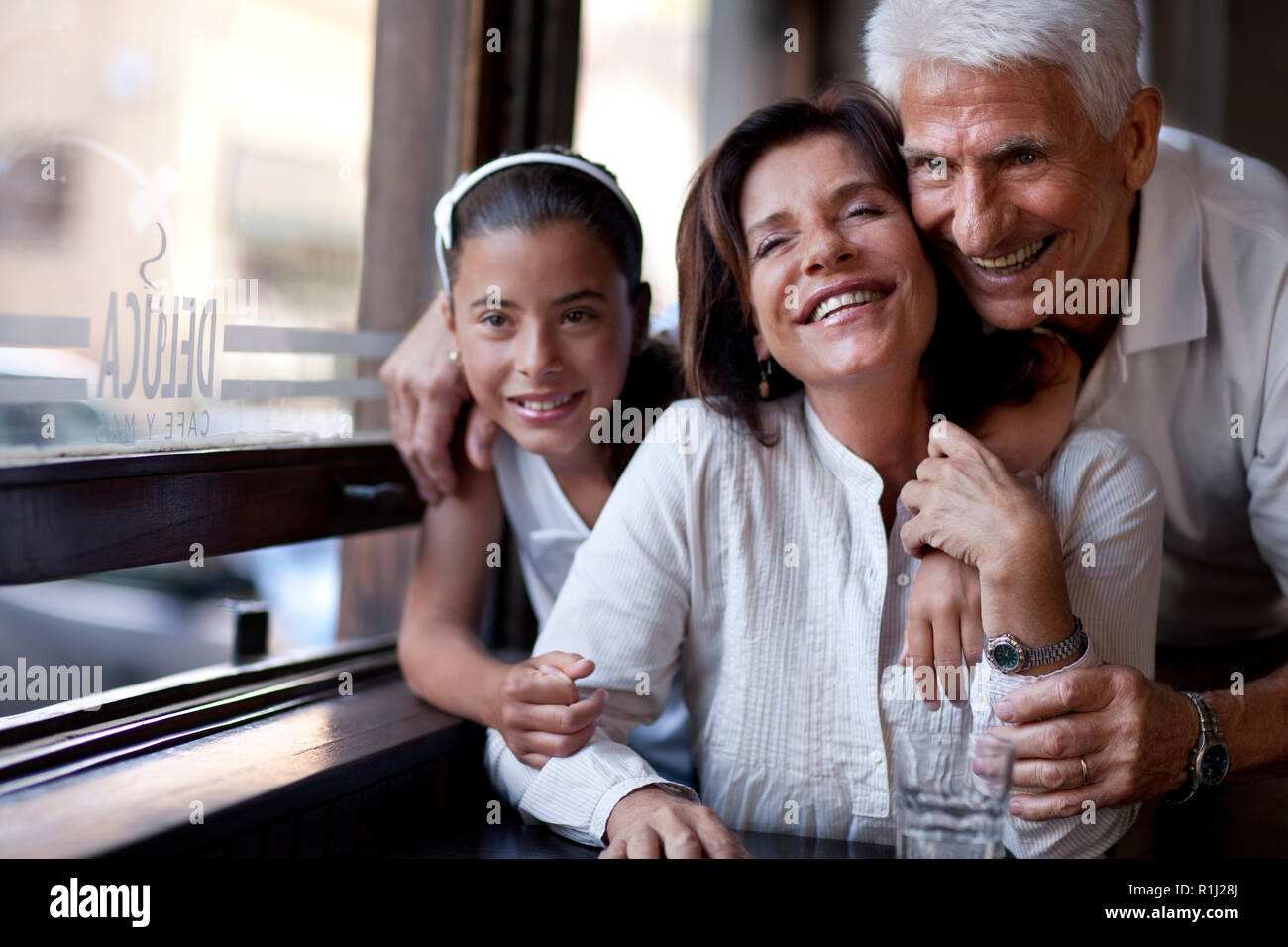 Happy family hugging in a cafe Stock Photo - Alamy