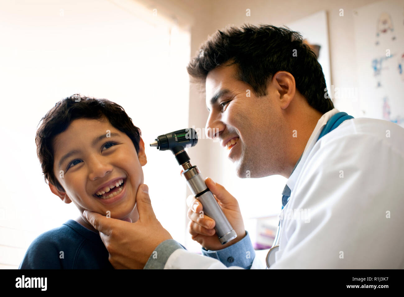 Doctor examining his young patient's ear with otoscope Stock Photo - Alamy