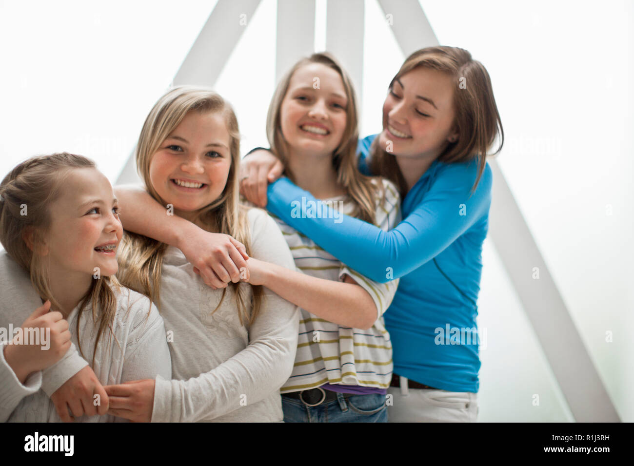 Portrait of four smiling sisters standing side by side with their arms ...
