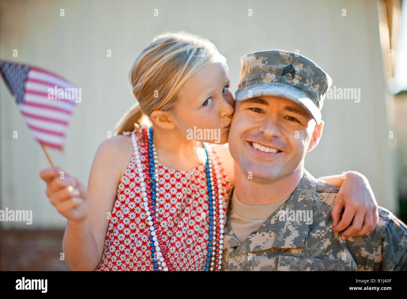 Portrait of a smiling soldier being kissed on the cheek by his young ...