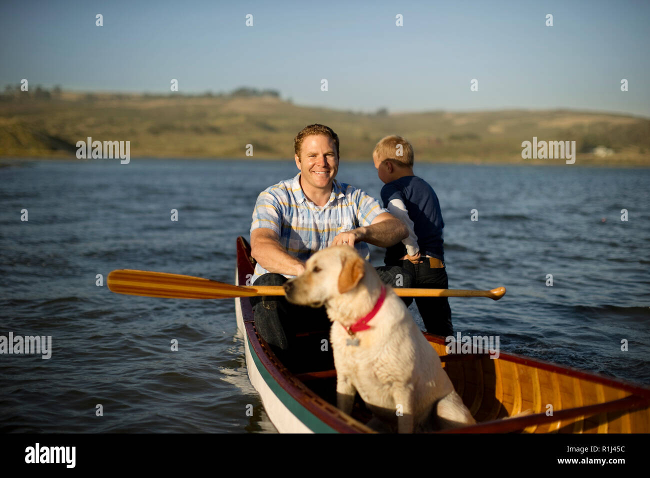 Mid adult man sitting in a canoe with his son and a labrador dog Stock ...