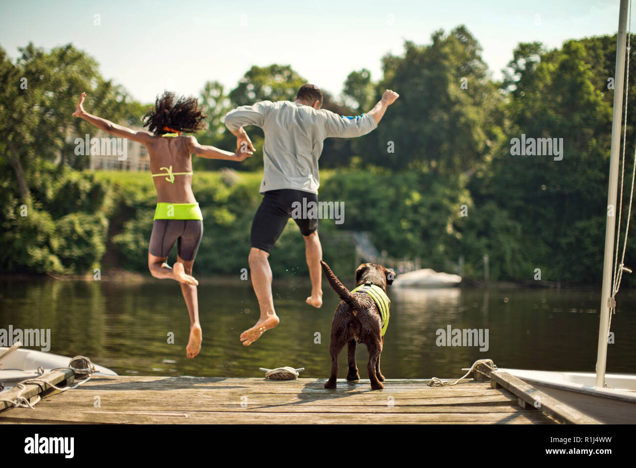 Happy young couple jumping off of a jetty Stock Photo - Alamy