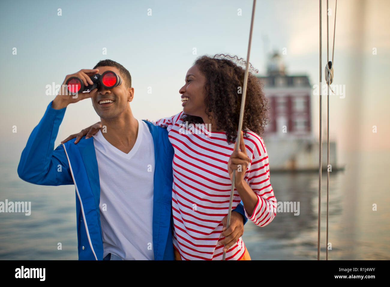 Happy young couple having fun with binoculars while sailing Stock Photo ...