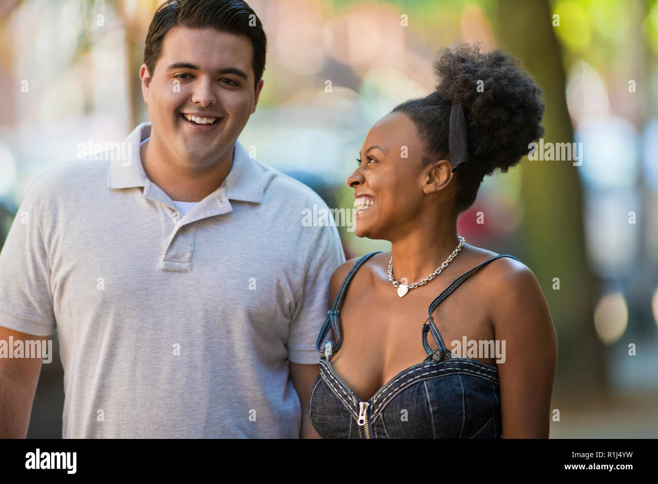 Happy young couple walking side by side down an urban street Stock ...