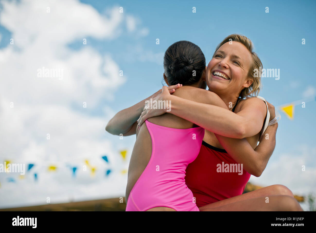 Two happy friends hug at the pool side Stock Photo - Alamy