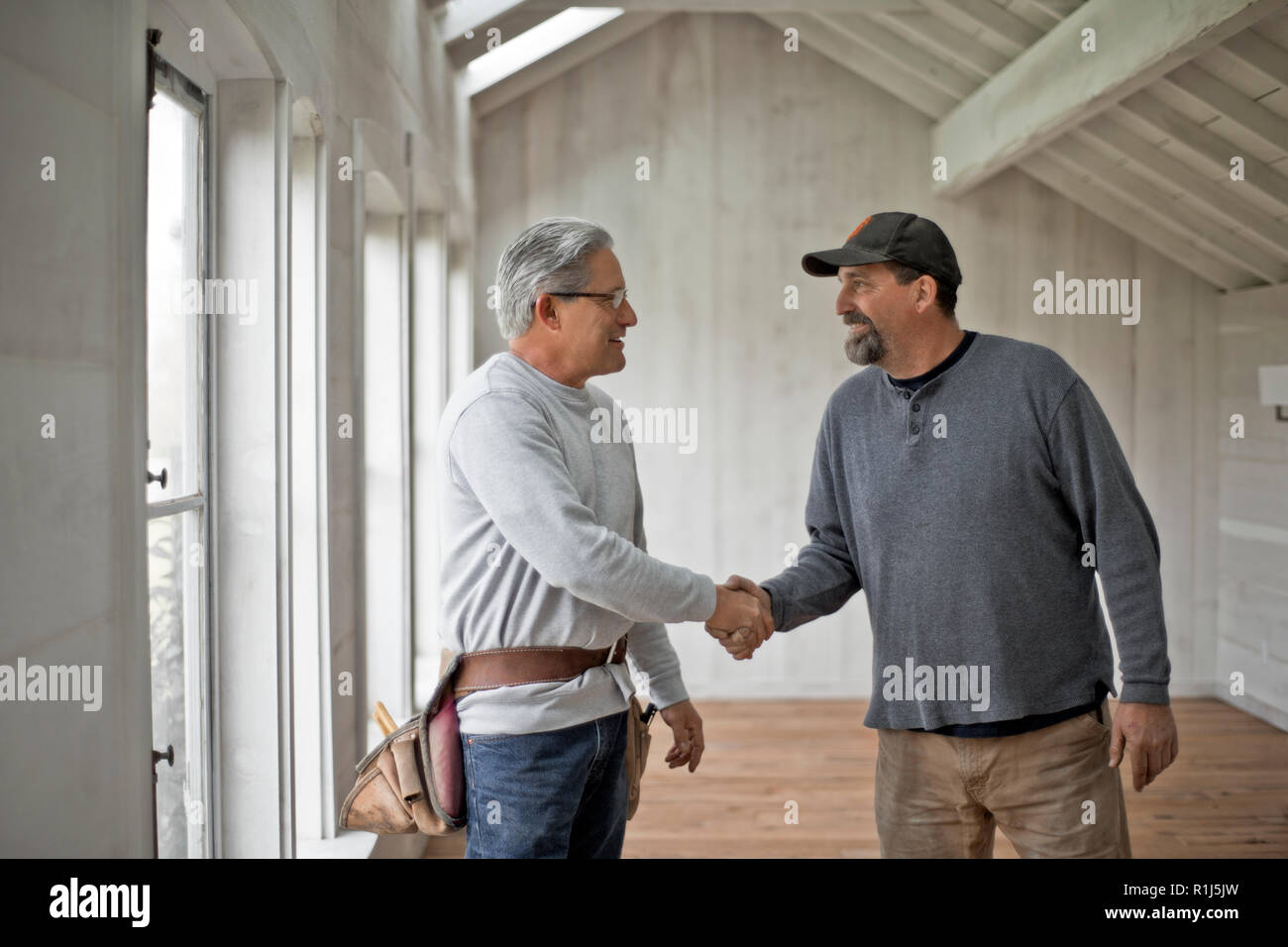 Builder shaking hands with client Stock Photo - Alamy