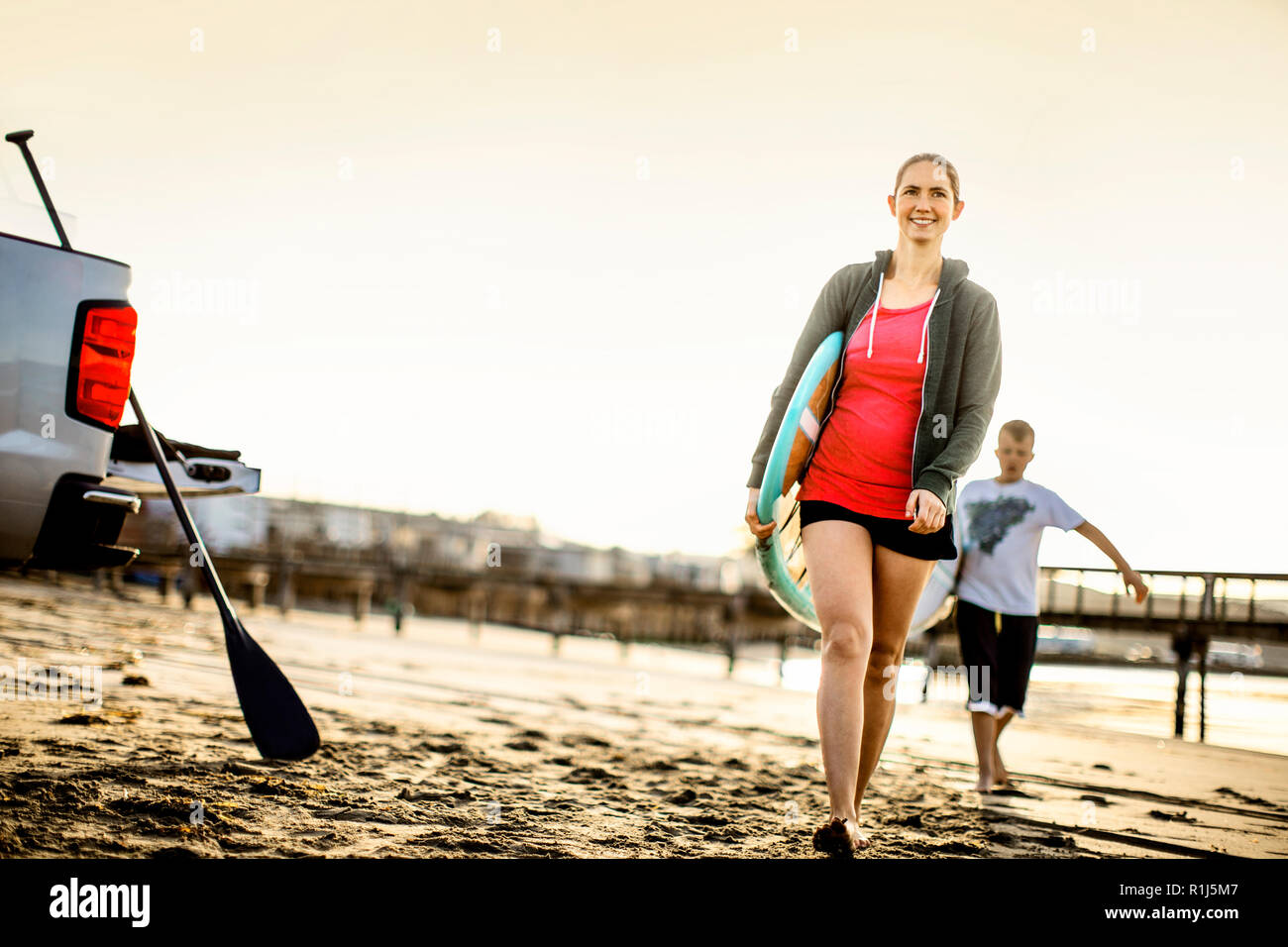 Mother and son carrying a paddleboard Stock Photo - Alamy