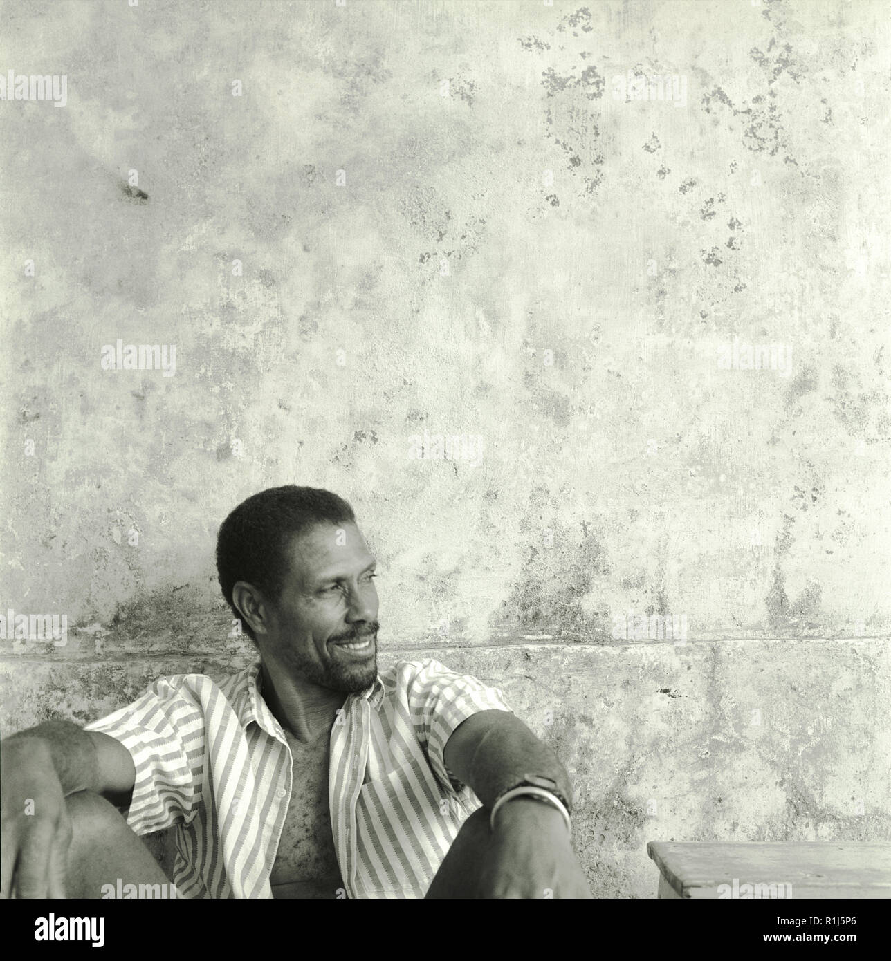 Side view of a man sitting against a wall Stock Photo - Alamy