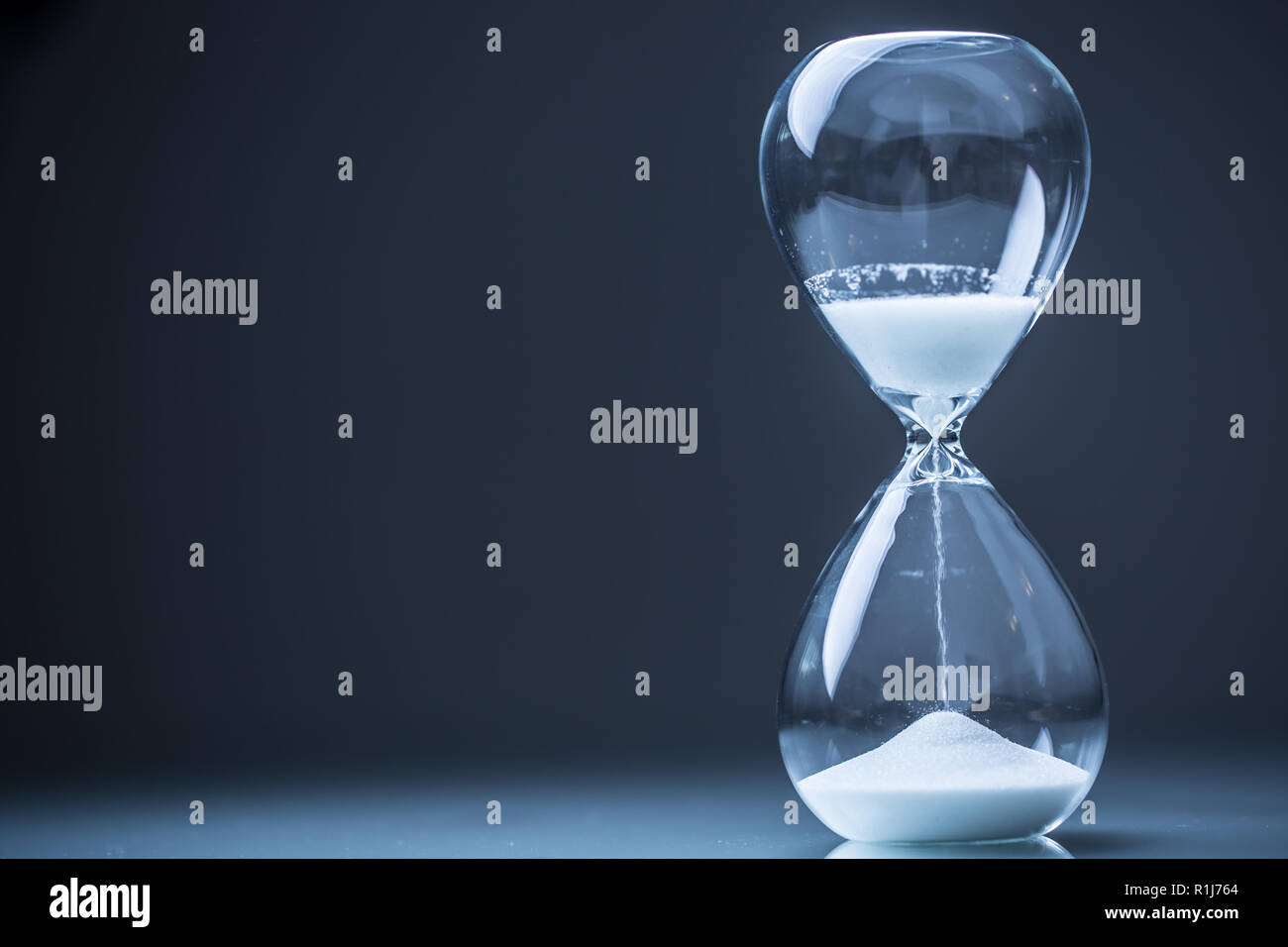 Modern hourglass in running time in studio lights Stock Photo - Alamy