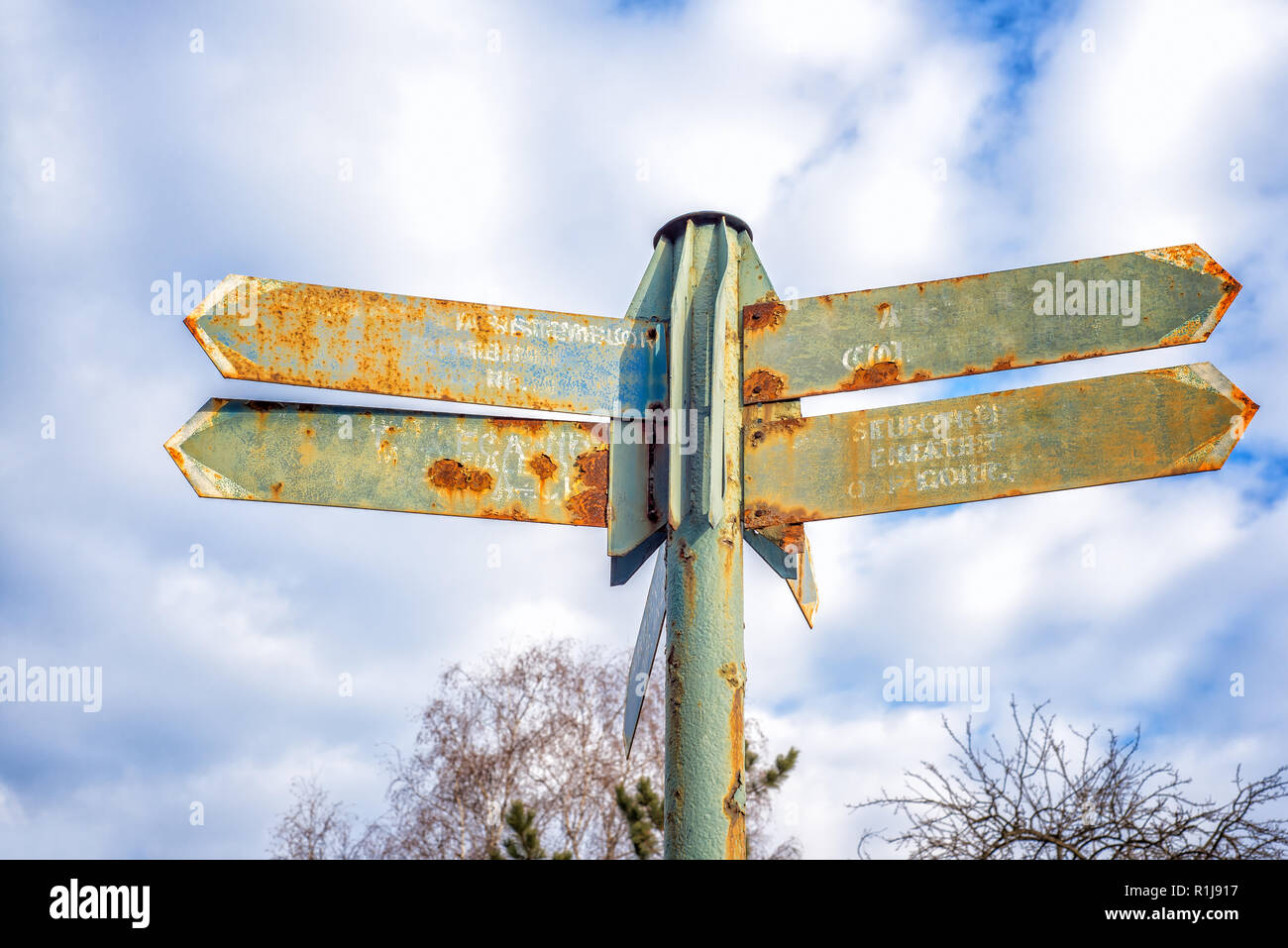 Old rusty street sign with arrows with clouds in background Stock Photo ...