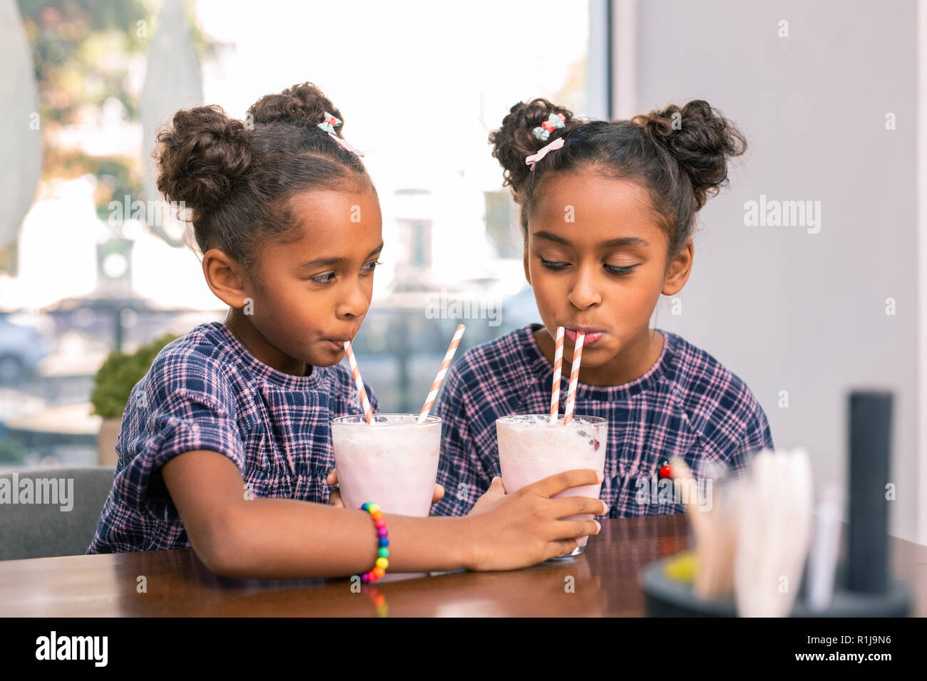 Cute kind-hearted sisters sharing their milk cocktails with each other ...