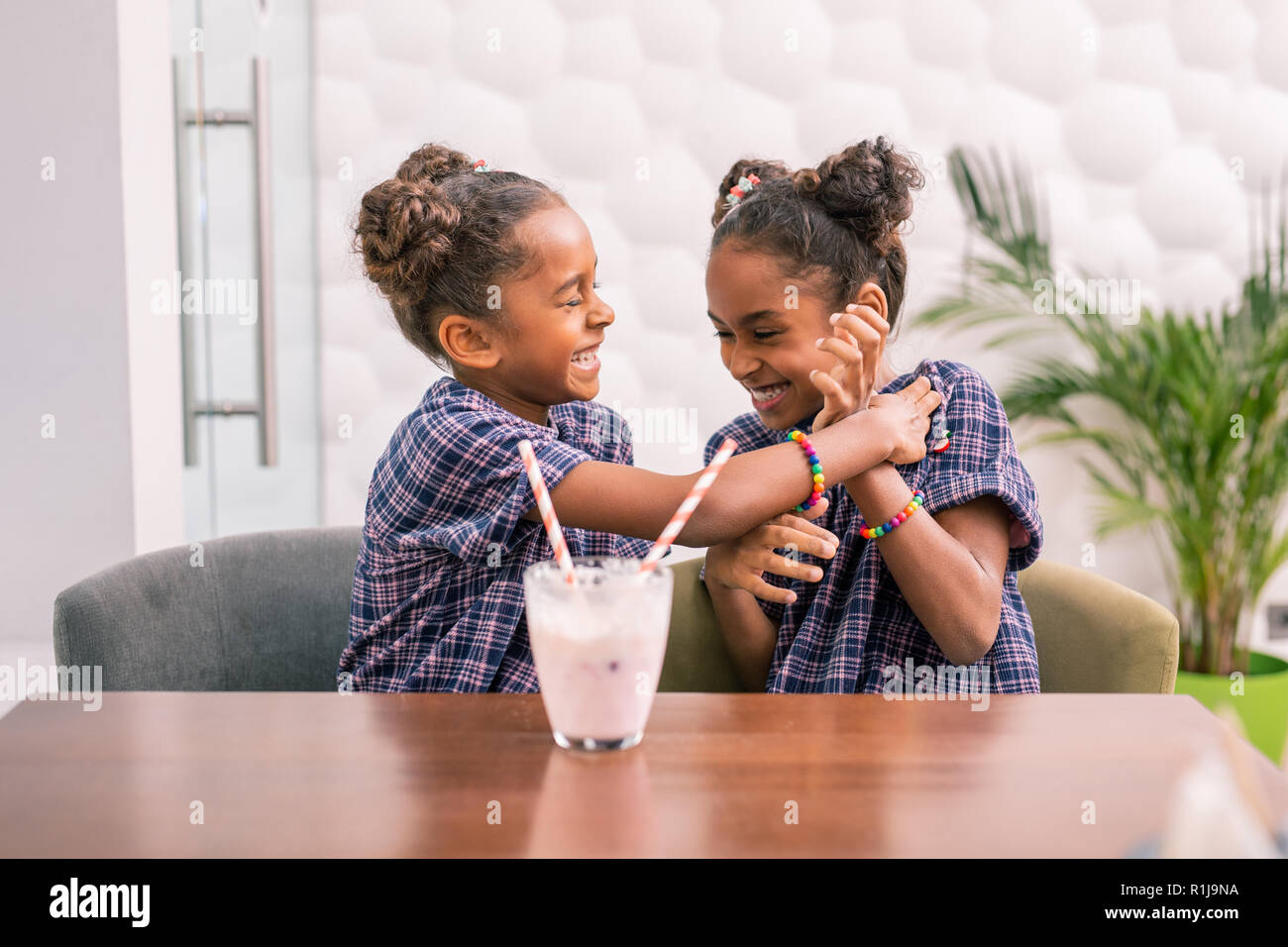 Little younger sister laughing out loud while hugging her smiling ...