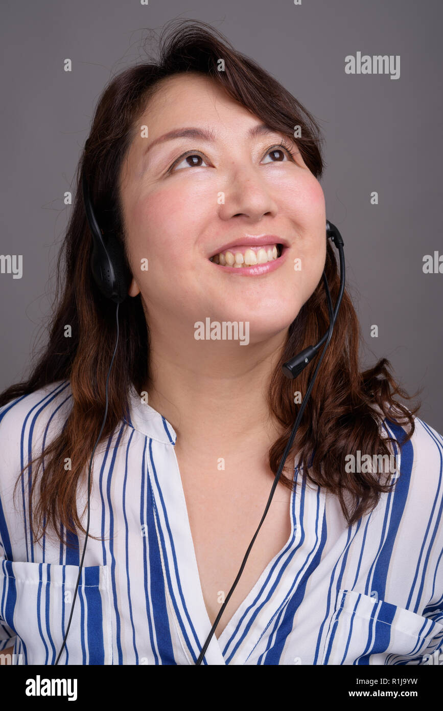Portrait of Asian call center representative woman thinking and smiling ...
