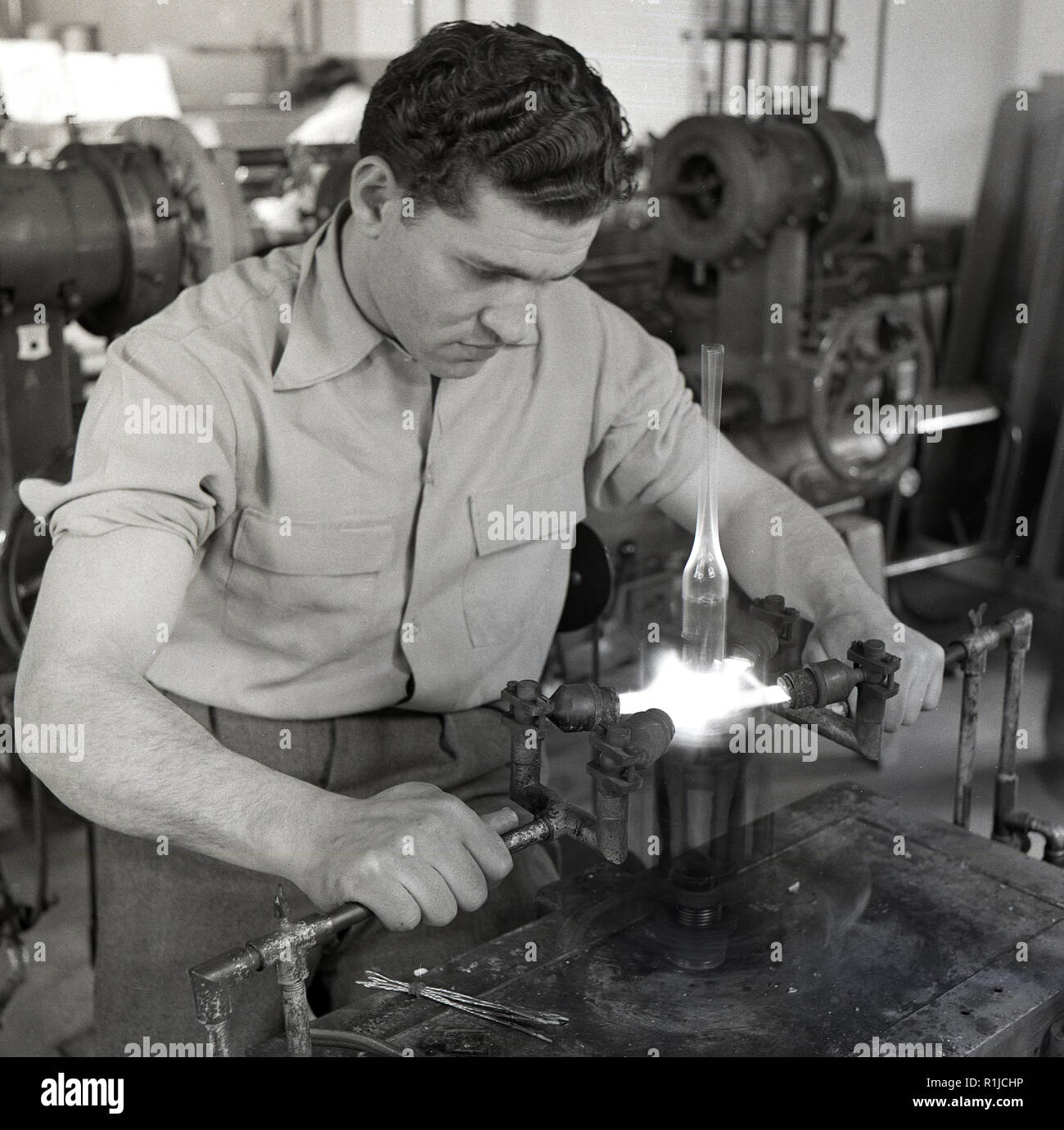 1950s, historical, a skilled male worker at a workbench using gas ...