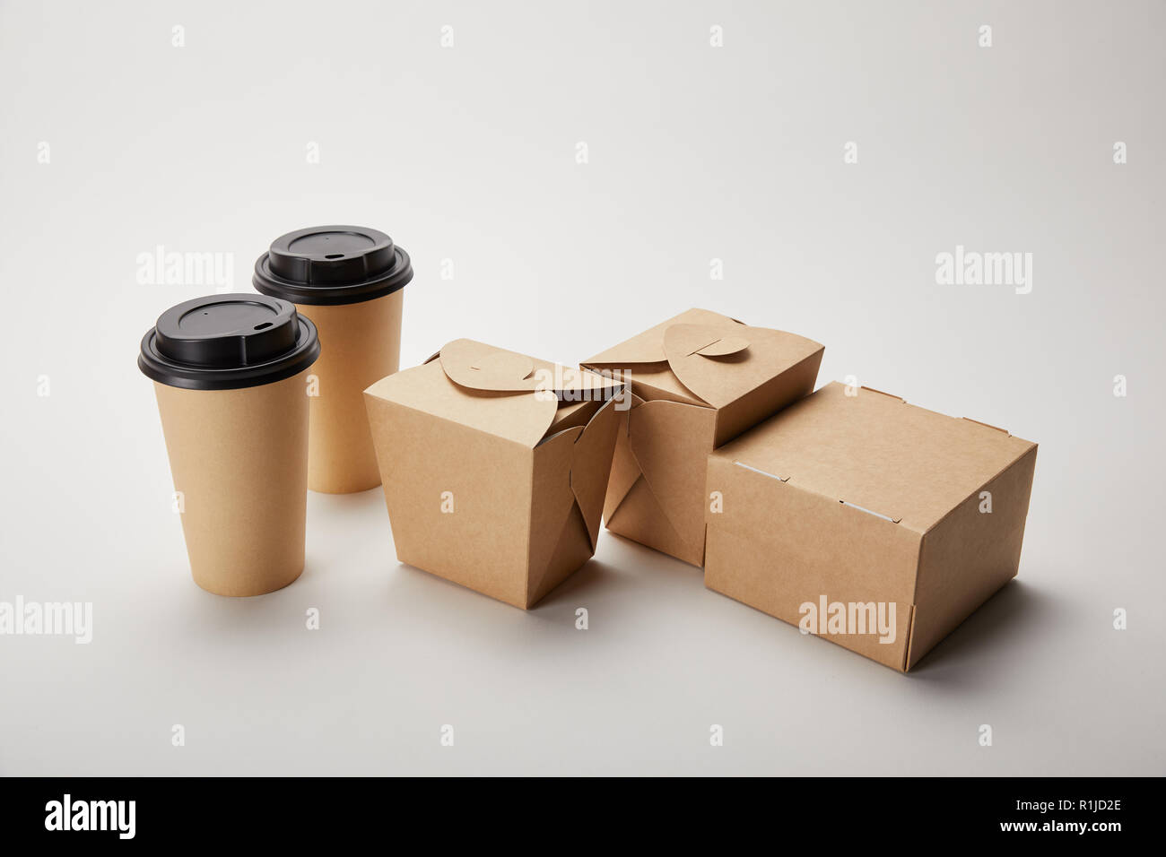 close up view of paper coffee cups and cardboard food boxes on white ...
