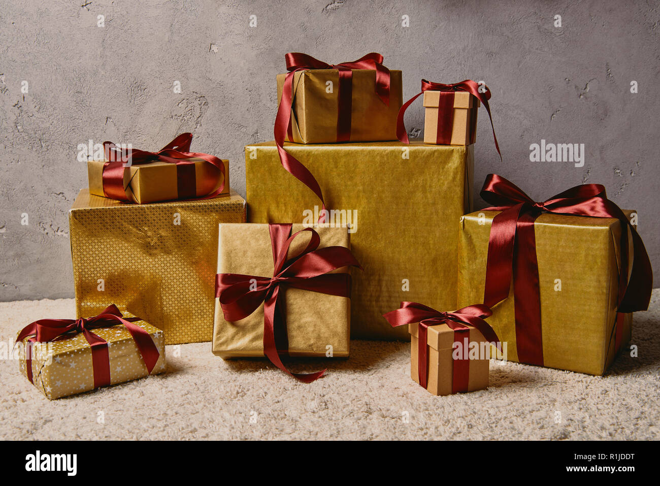 pile of golden Christmas gift boxes on carpet in room Stock Photo - Alamy
