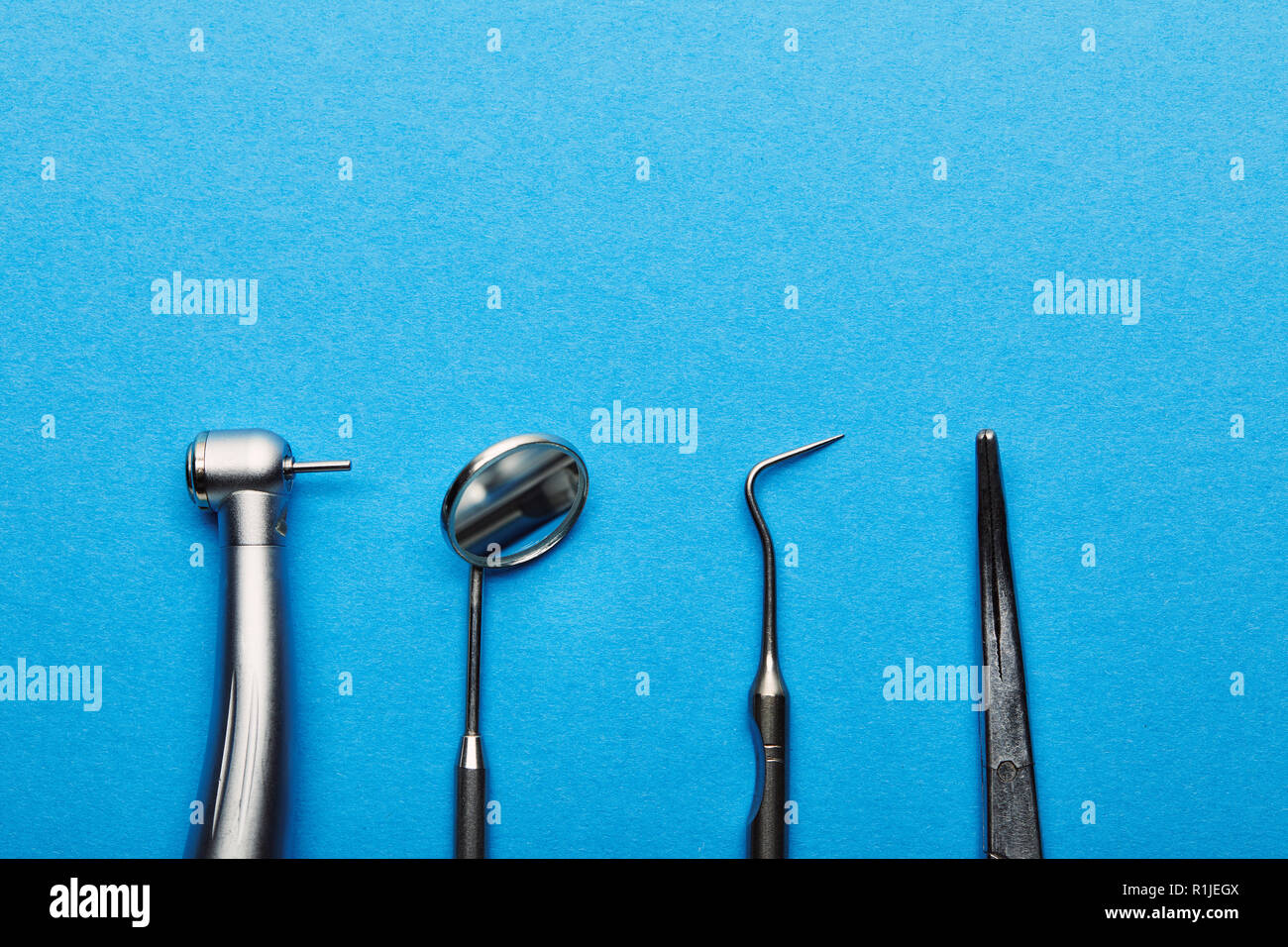 flat lay with arranged stainless dental instruments on blue tabletop ...