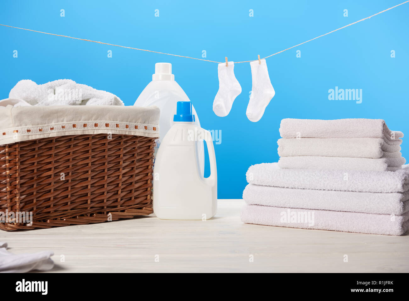 laundry basket, plastic containers with laundry liquids, pile of clean ...