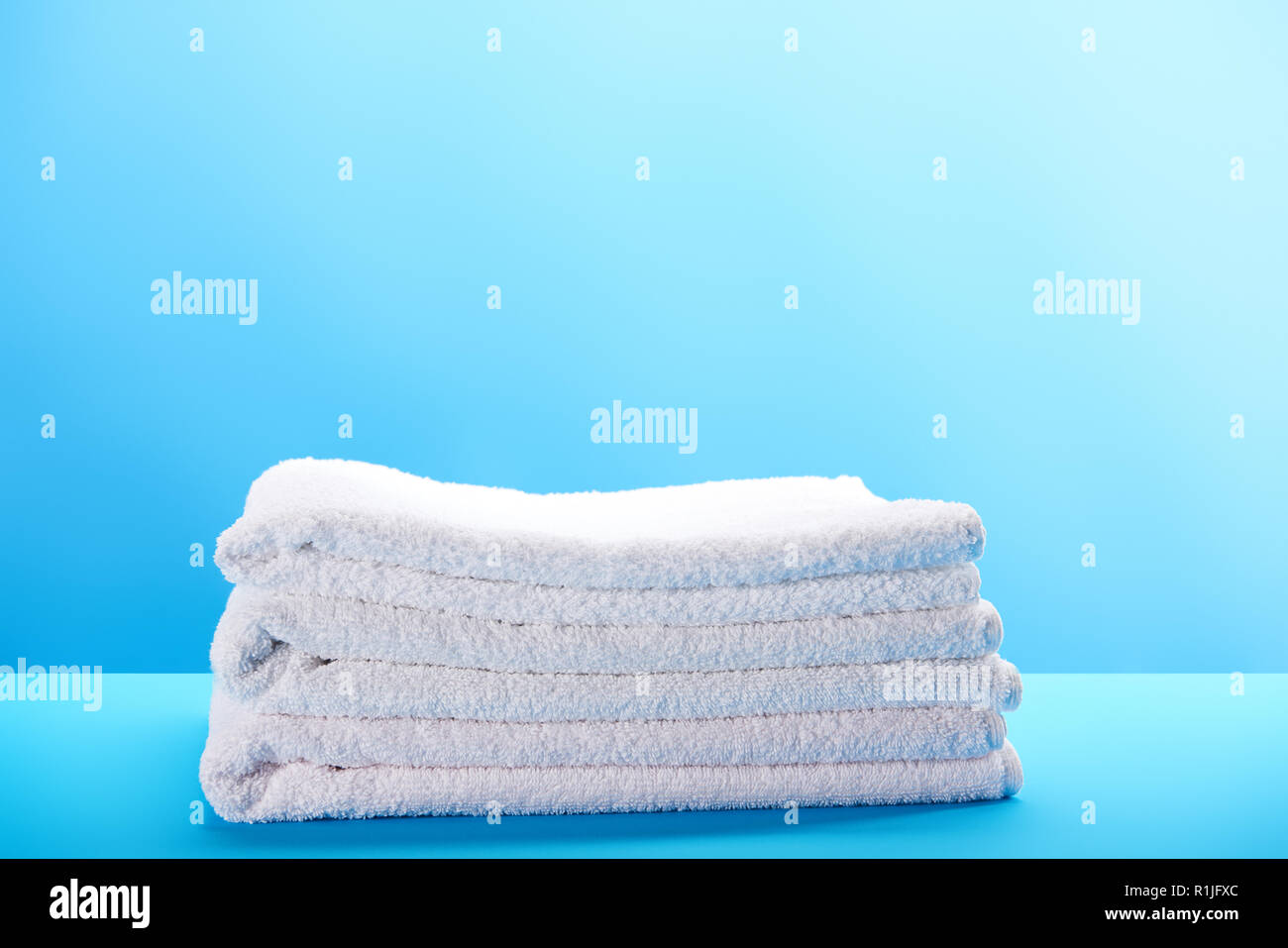 pile of clean soft white towels on blue background Stock Photo - Alamy