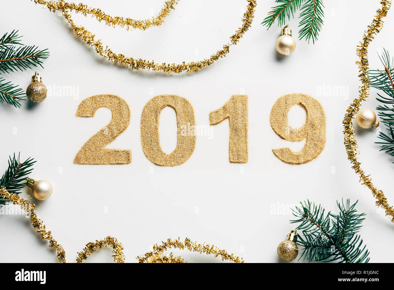 top view of 2019 year sign, pine branches, golden garlands and ...
