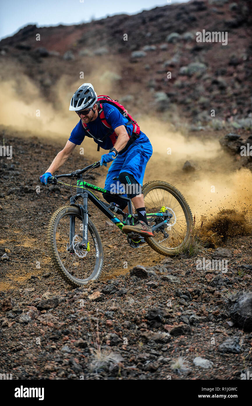 A man rides a mountain bike on volcanic terrain near la Piton de la ...