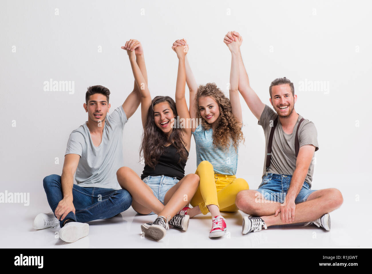 Portrait of joyful young group of friends sitting on the ground in a ...