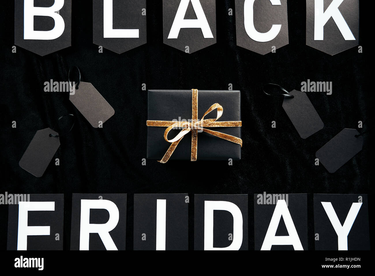 top view of black friday lettering, wrapped gift and blank price tags ...