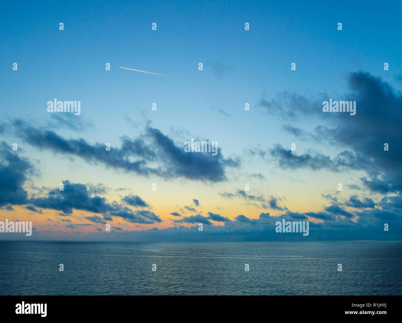The trail of a jet over the sea on the background of a beautiful Golden ...