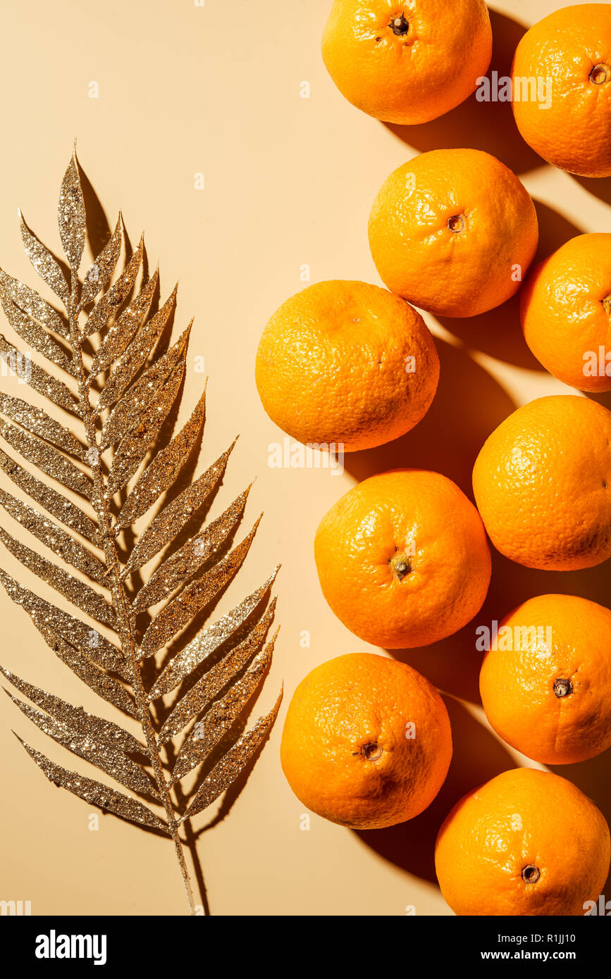 Top view of tangerines and decorative golden twig on beige backdrop ...