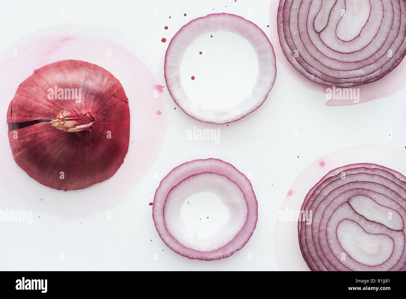top view of red onion with slices and rings on white surface with pink ...
