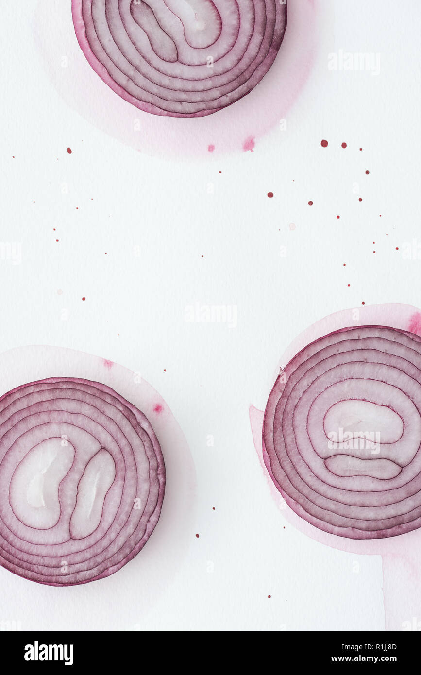 top view of sliced red onion on white surface with pink watercolor ...