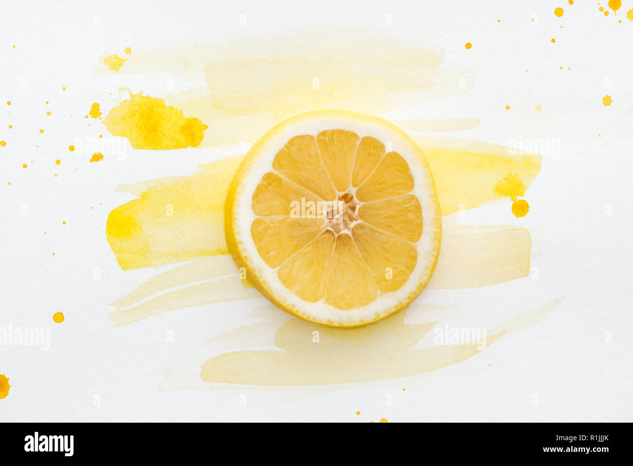 elevated view of lemon piece on white surface with yellow watercolor ...