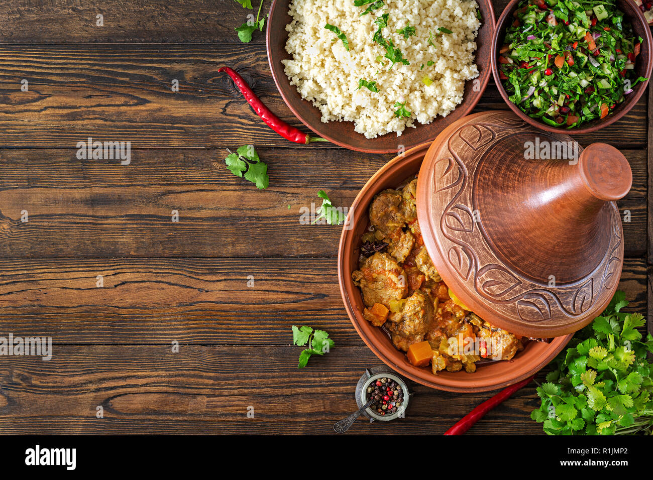 Traditional tajine dishes, couscous and fresh salad on rustic wooden ...