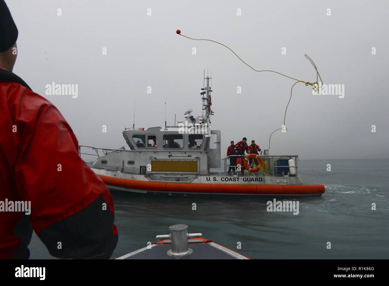 Coast Guard Petty Officer 3rd Class Alex Sheltra prepares to receive a ...