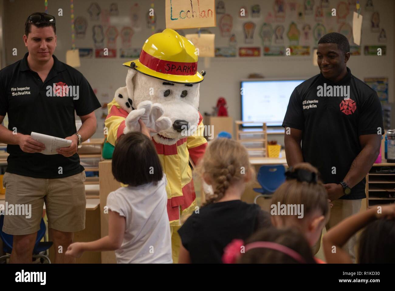 A child high-fives Sparky the Fire Dog before a fire safety briefing ...