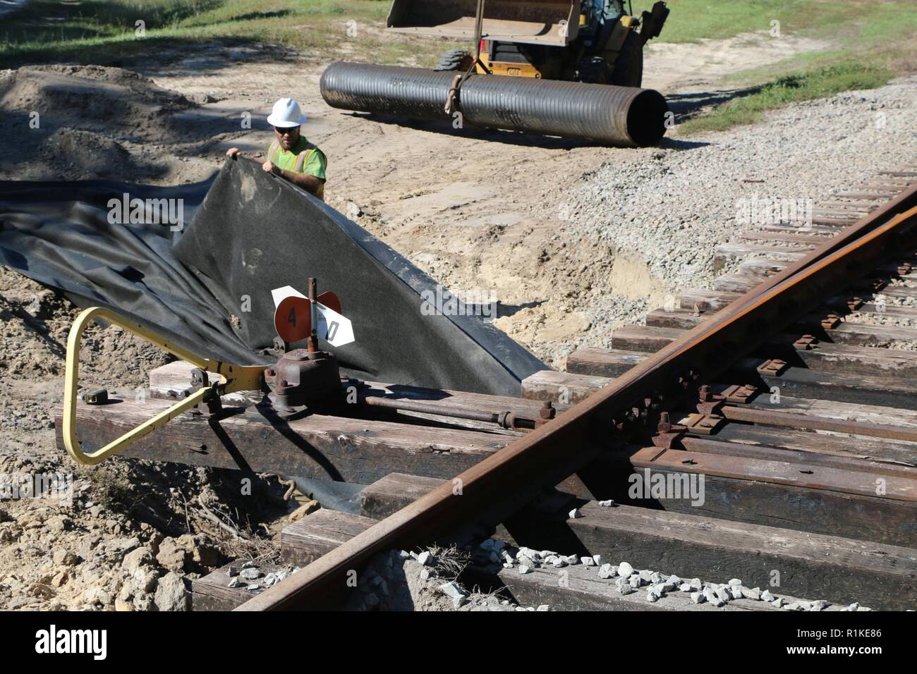 Contractors install a culvert under a portion of a washed out rail line ...